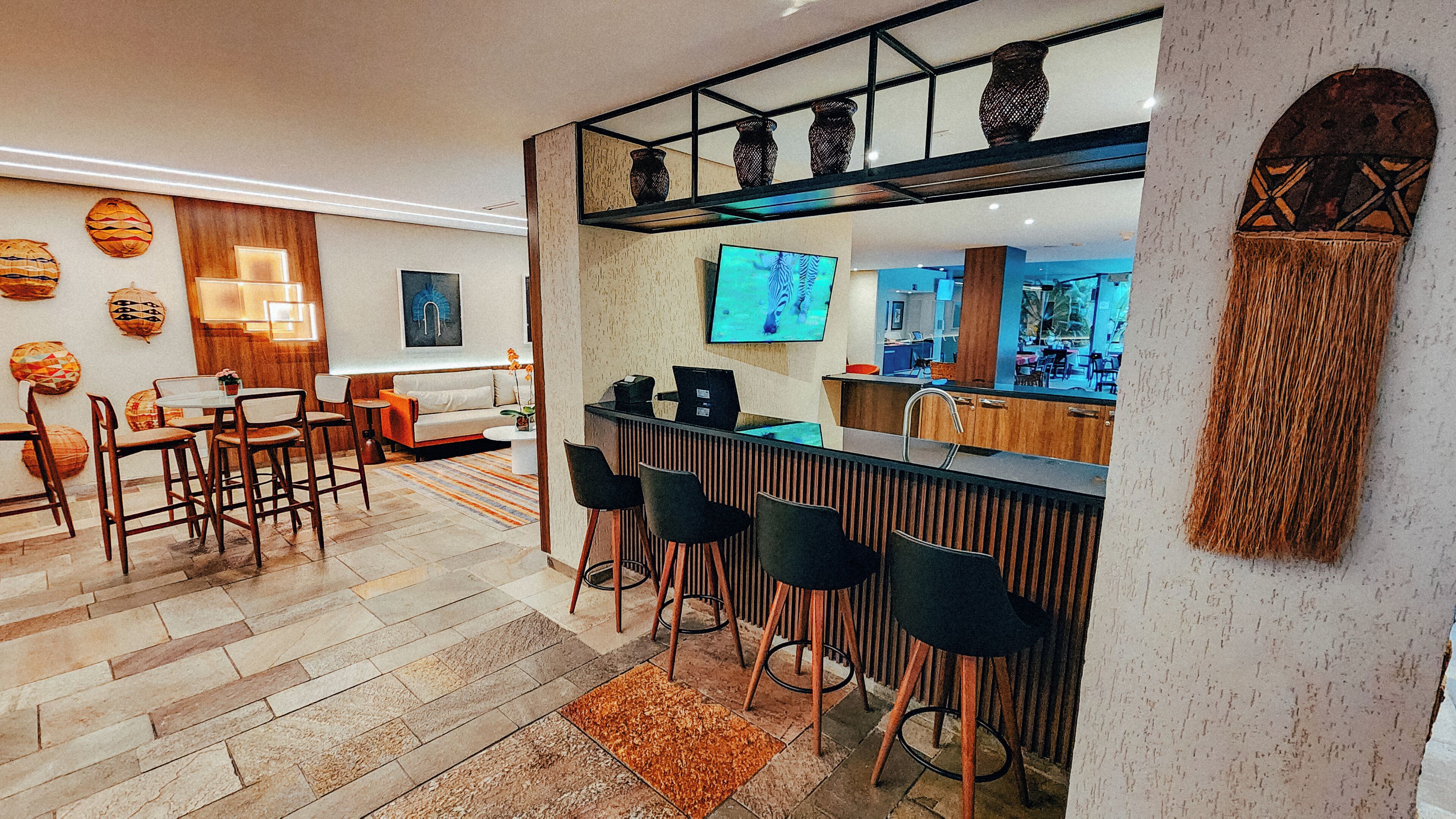Cozinha moderna com área de bar, banquetas de madeira e televisão.