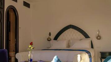 Quarto de hotel com uma cama, um vaso com uma flor e um cobertor listrado em azul e branco.