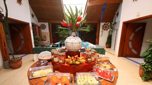 Mesa de buffet com diversos alimentos e um arranjo decorativo.