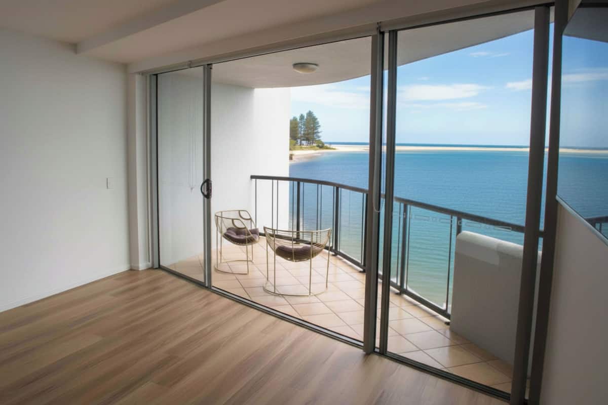 Uma varanda com vista para o mar, chão de madeira e duas cadeiras.