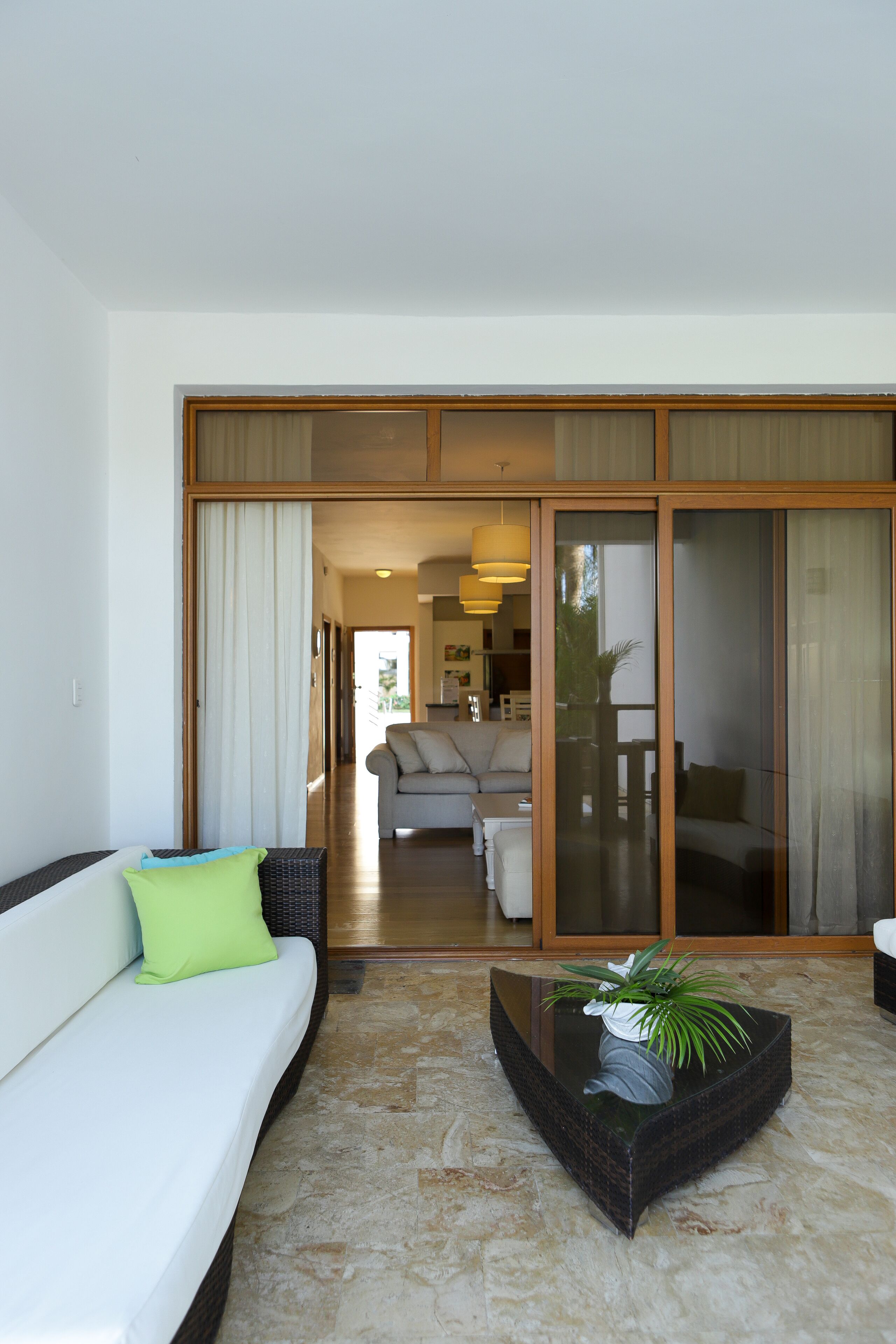 Uma sala de estar moderna com um sofá, uma mesa de centro e uma porta de vidro deslizante que dá para uma sala de jantar.