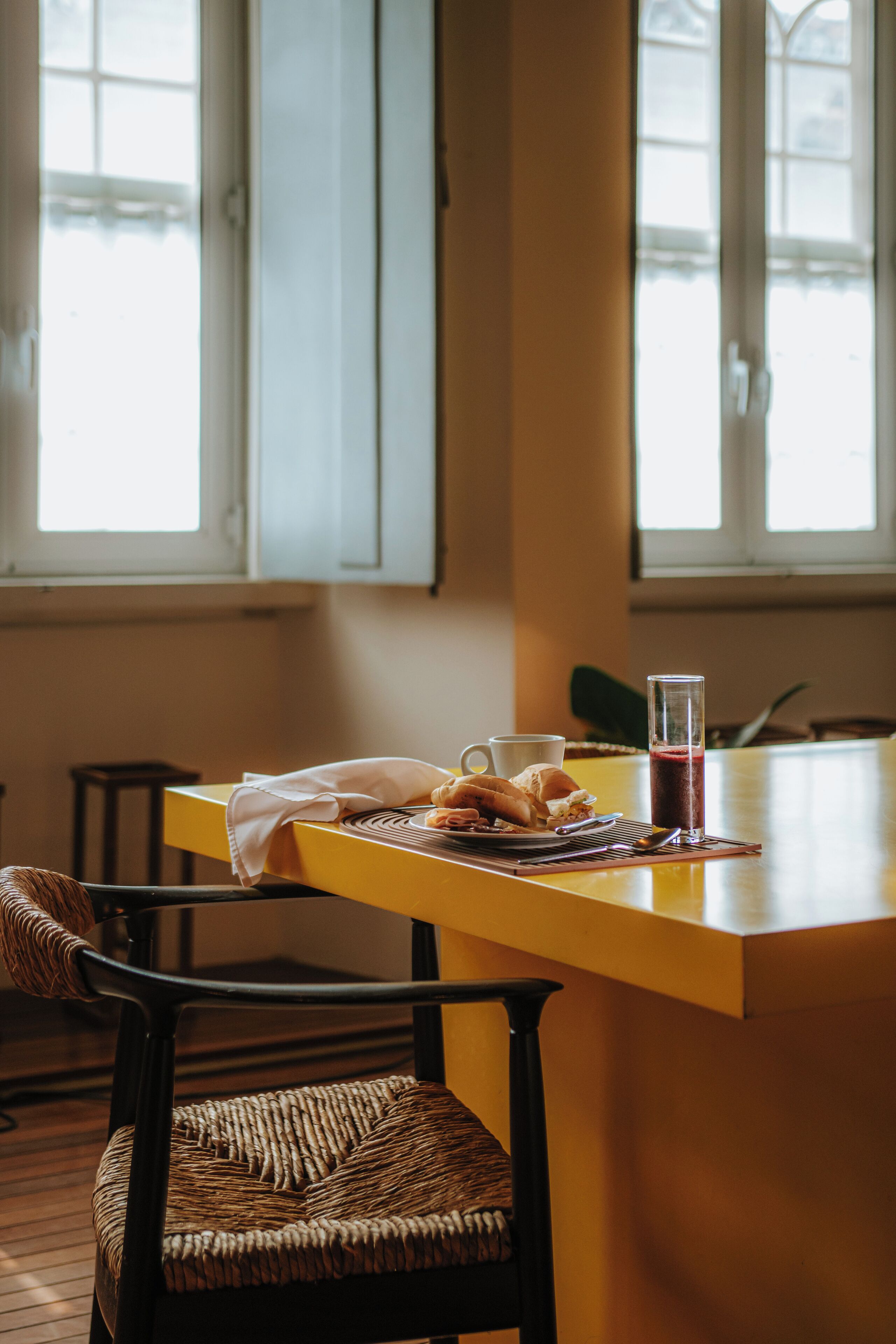 Uma mesa de jantar com uma refeição, um copo de suco e uma cadeira com assento de fibra.