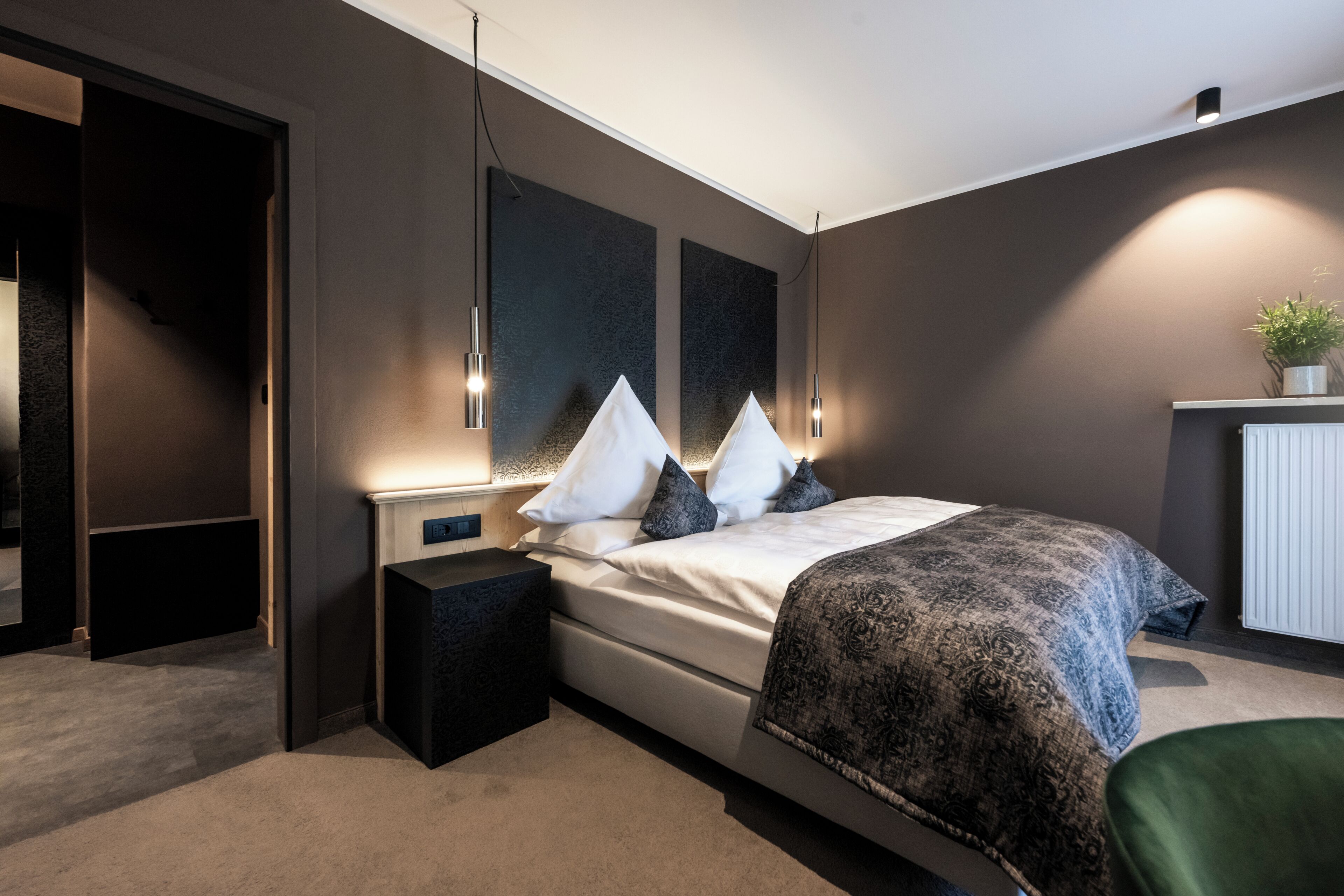 Um quarto moderno com uma cama grande, mesas de cabeceira e uma luminária na parede.