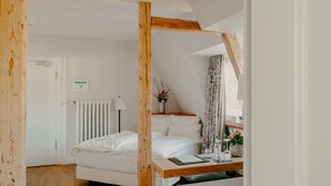 Um quarto com uma cama de dossel de madeira, um radiador branco, uma mesa de cabeceira com abajur e uma janela com cortinas.