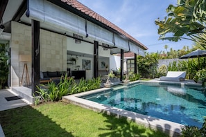Uma casa moderna com piscina, área de estar externa e vegetação exuberante.