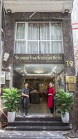 Entrada do Hotel Boutique Splendid Star com fachada de mármore, grandes janelas e um candelabro.