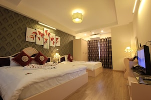 Quarto de hotel com uma cama grande, televisão e escrivaninha.