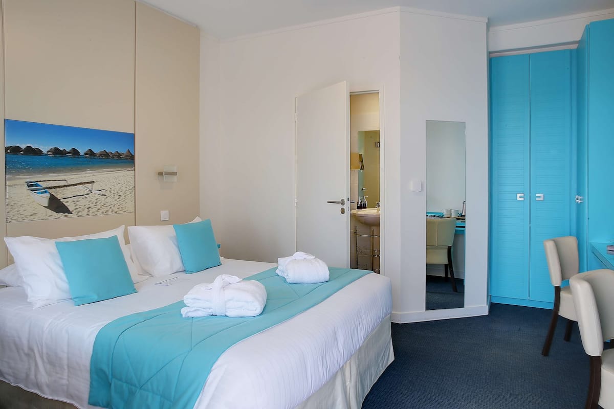 Quarto de hotel com cama, banheiro e vista para a praia.