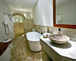 Um banheiro moderno com uma banheira de pé, uma pia oval grande e um espelho sobre a pia.