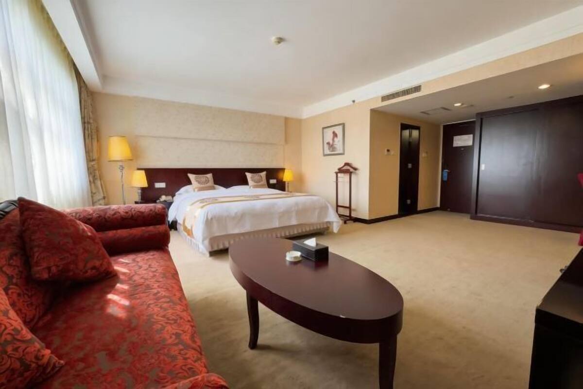 Quarto de hotel com uma cama, um sofá, uma mesa de centro e uma porta.