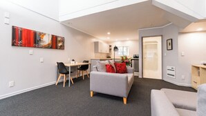 Um apartamento moderno com um sofá cinzento, uma área de refeições, uma cozinha e uma sala de estar.