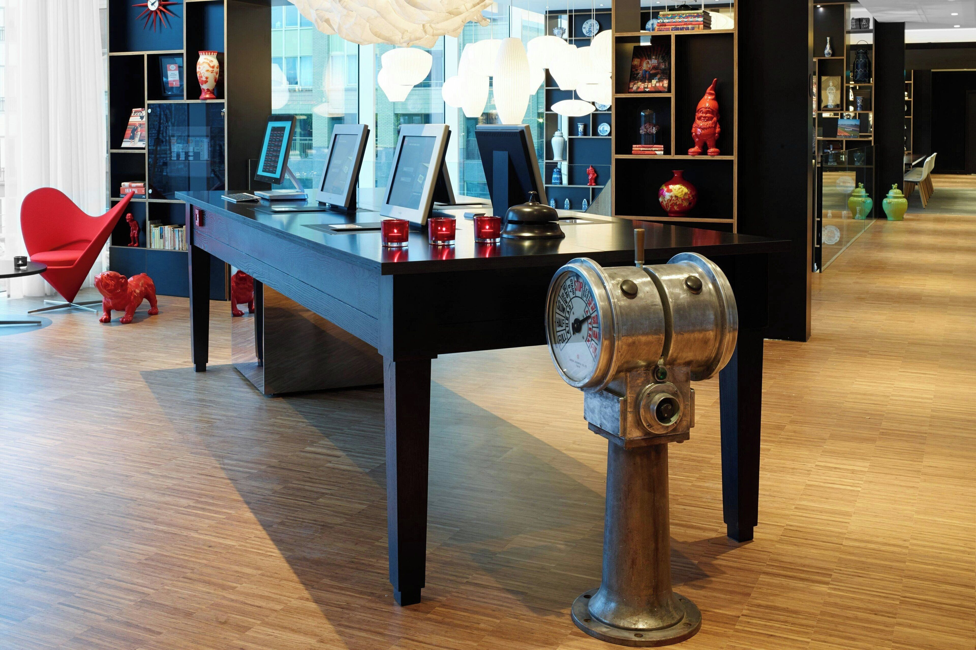 Um interior moderno com soalho de madeira, uma escrivaninha preta com manómetro de estilo vintage e uma cadeira vermelha.