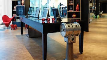 Um interior moderno com soalho de madeira, uma escrivaninha preta com manómetro de estilo vintage e uma cadeira vermelha.