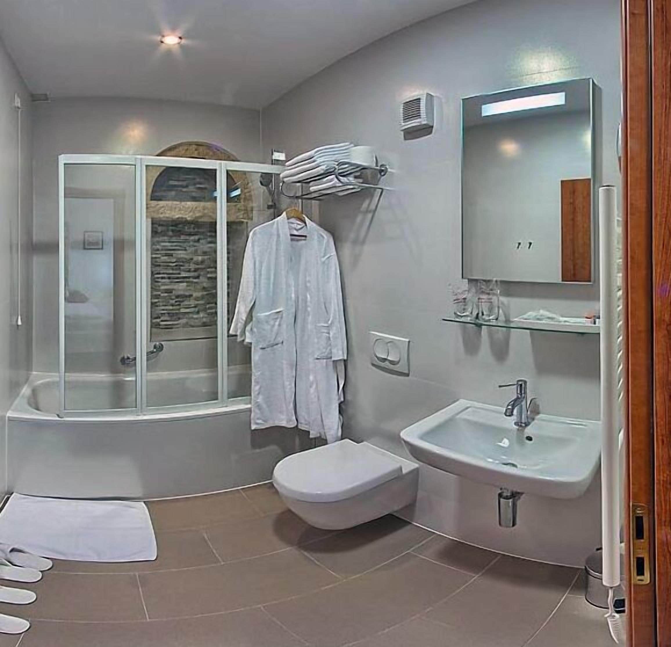 Casa de banho moderna com cabine de duche em vidro, sanita, lavatório e espelho.