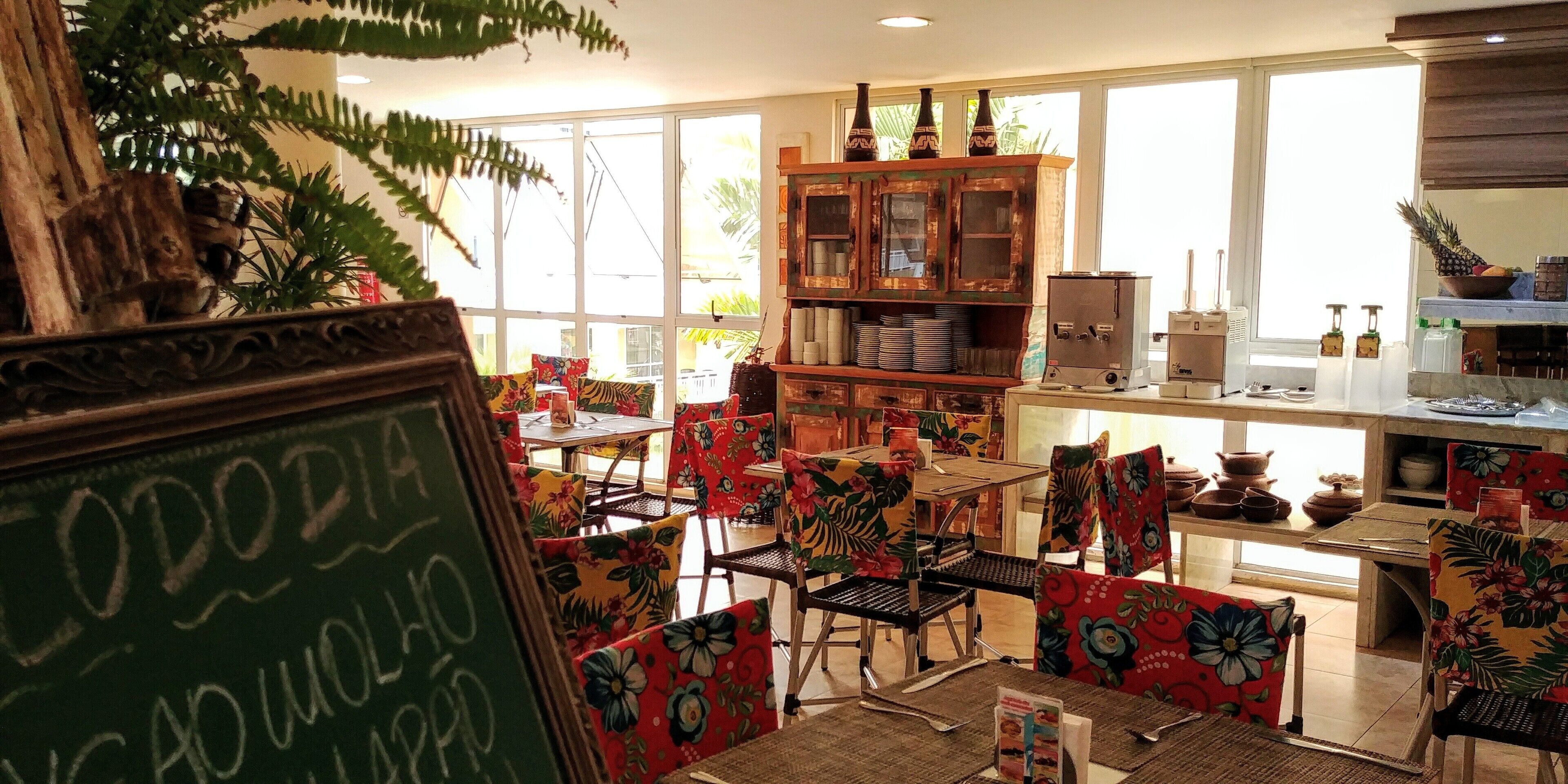 Um restaurante com uma janela grande, armários de madeira e cadeiras coloridas.