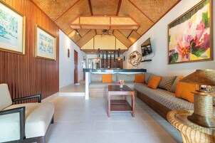 Uma sala de estar ampla com teto alto, um sofá, uma mesa de centro e uma mesa de jantar.