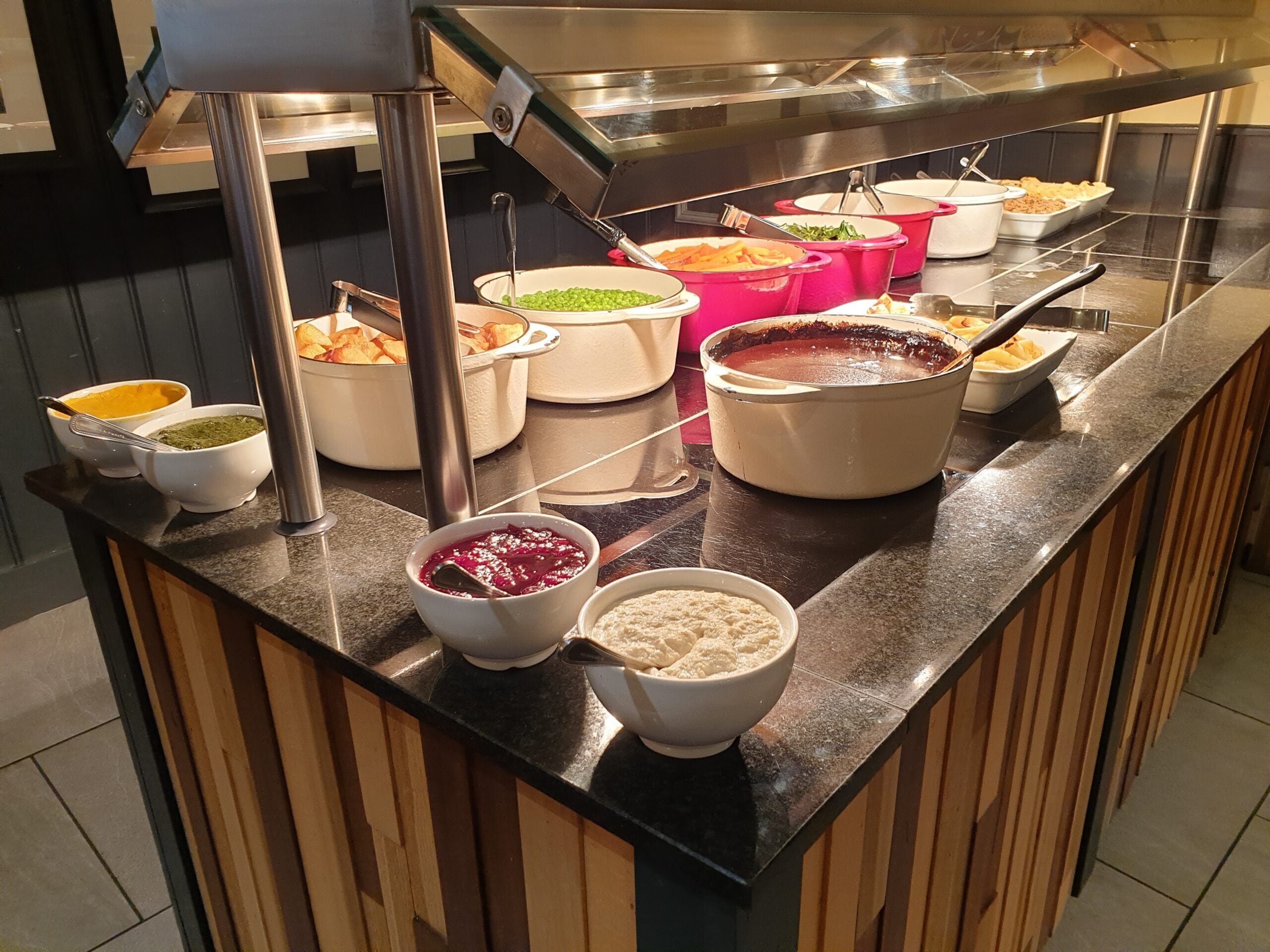 Um balcão de buffet com diversos alimentos e utensílios de servir.