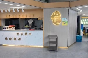 Uma área de recepção com balcão, parede com placa decorativa e espaço para sentar.