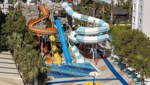 Um parque aquático com várias escorregas e uma área de piscina com guarda-sóis e espreguiçadeiras.