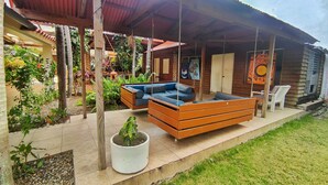 Uma cabana de madeira com varanda coberta, área de estar externa e um vaso de planta.