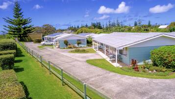 Uma fileira de cabanas modernas, de um andar, equipadas com painéis solares, um acesso pavimentado e um jardim bem cuidado.