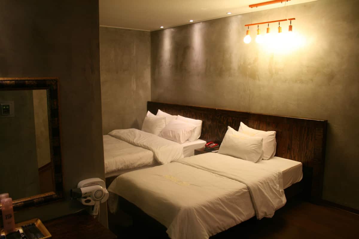 Quarto de hotel com duas camas, um espelho, um secador de cabelo e uma mesa de cabeceira.