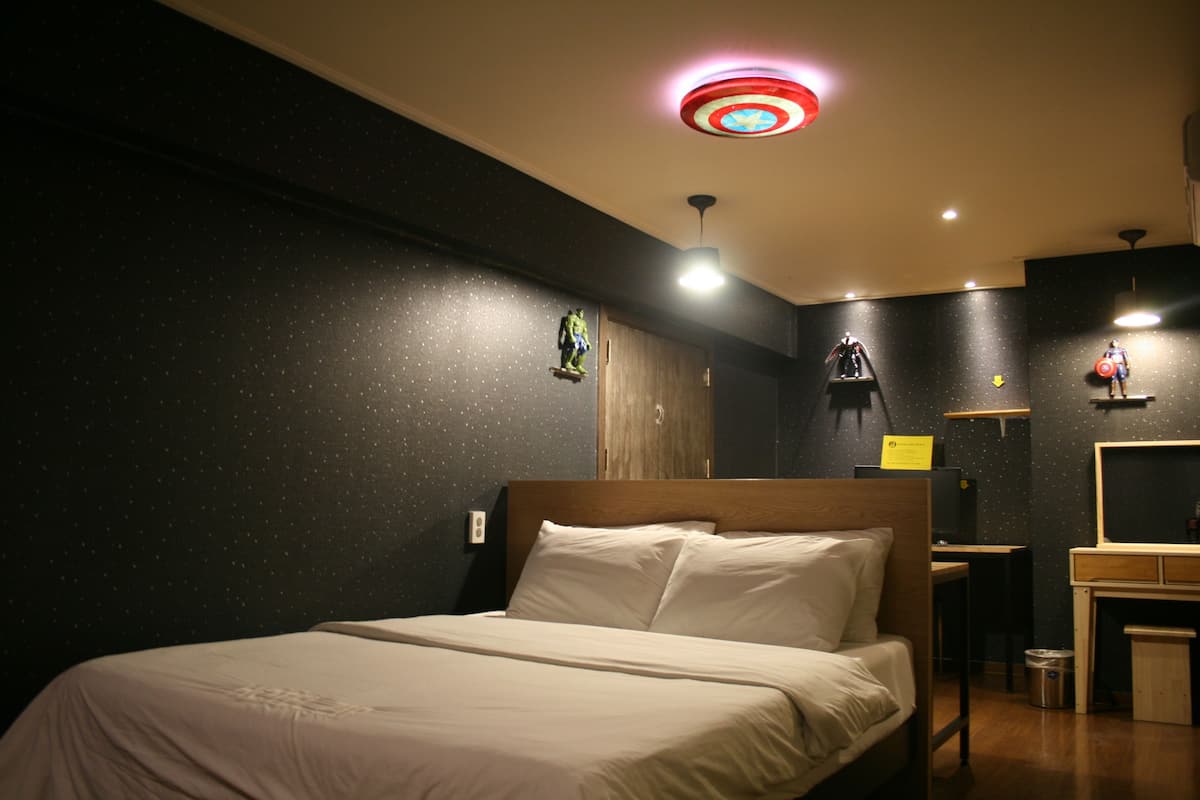 Quarto de hotel com uma cama, uma mesa e um espelho.