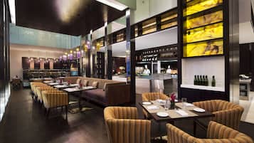 Restaurante moderno com área de bar, assentos com cadeiras listradas e painel de mármore.
