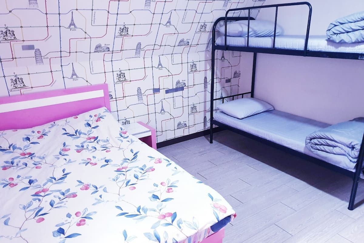 Um quarto com beliche, cama de solteiro com roupa de cama florida e papel de parede com mapa.