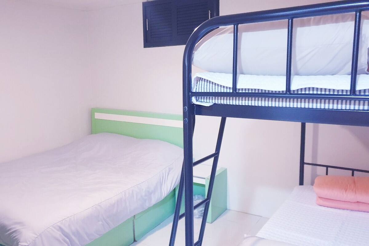 Uma cama box com estrutura verde e uma cama de solteiro com colchão branco.