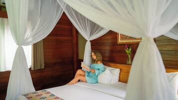 Quarto com cama, cortinas brancas e cabeceira de madeira.