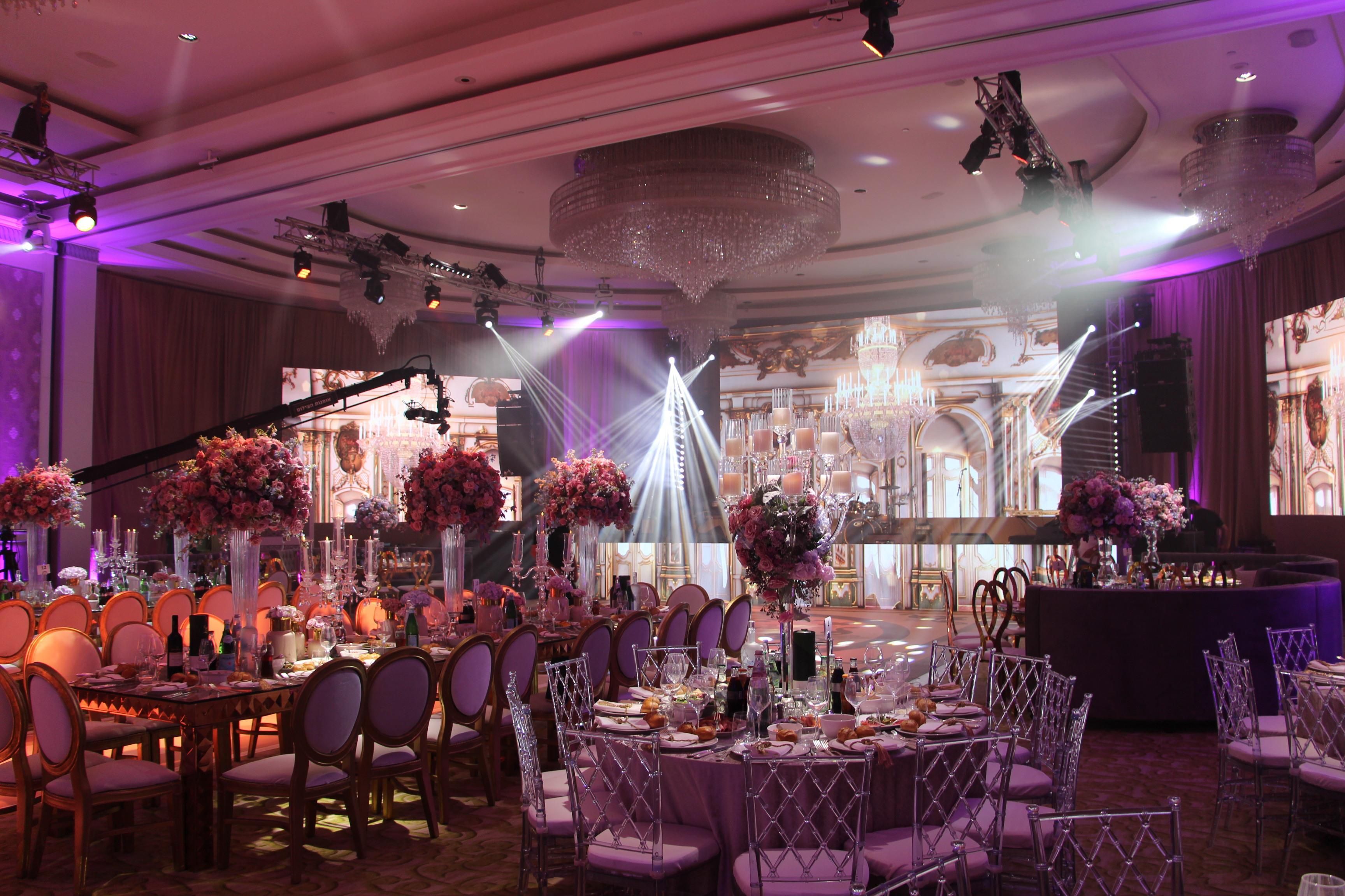 Uma sala de banquetes com mesas redondas, cadeiras e centros de mesa florais.