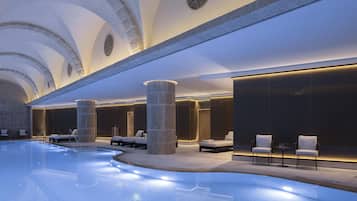 Piscina interior moderna com áreas de estar e pilares de pedra.