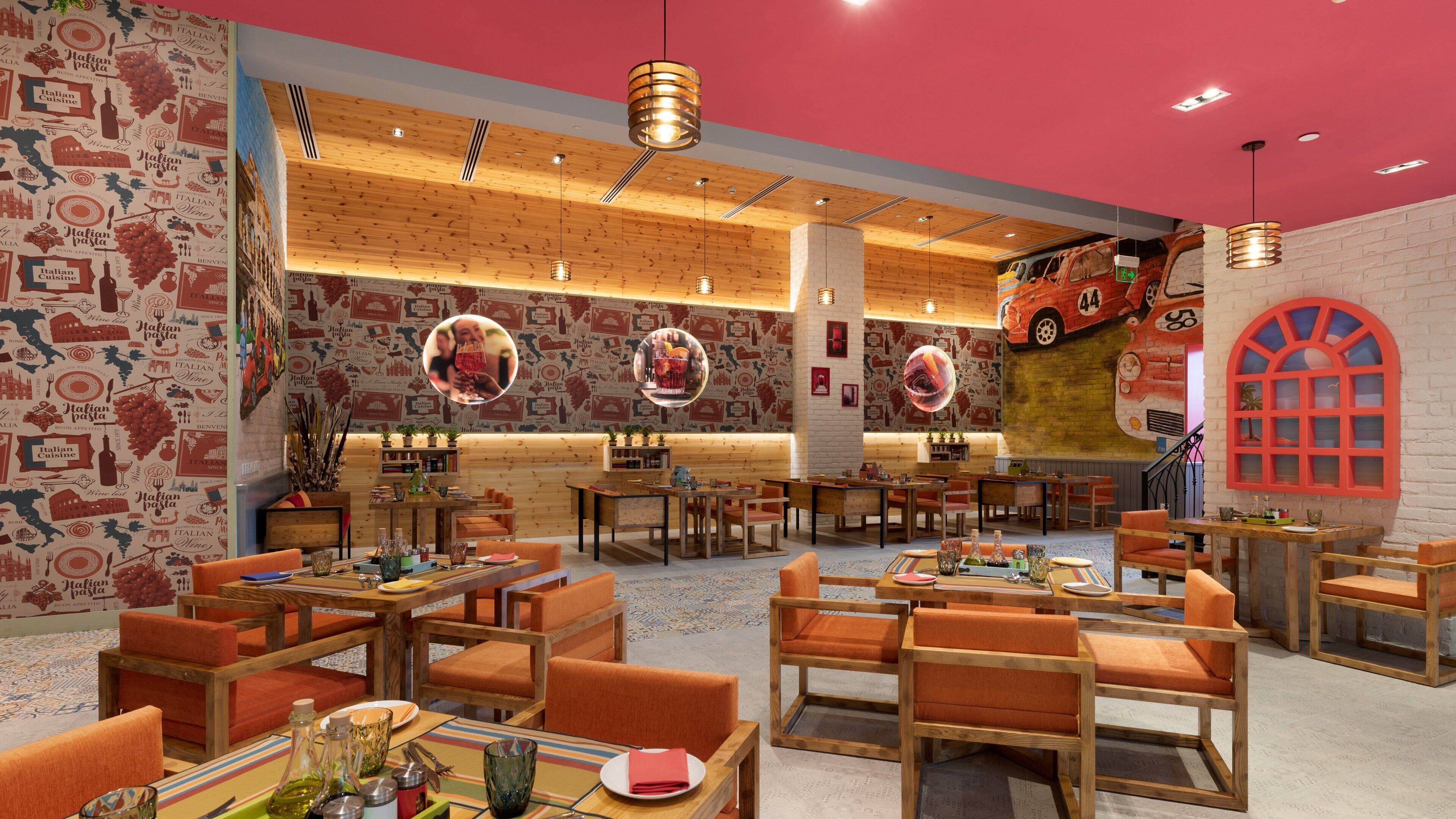 Restaurante com móveis de madeira, paredes vermelhas e um mural de carro.