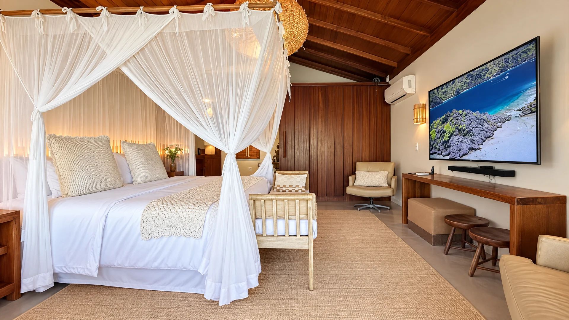 Quarto com cama de dossel, televisão e vista para a costa rochosa.