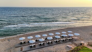 Na praia, espreguiçadeiras, guarda-sóis de praia, toalhas de praia 