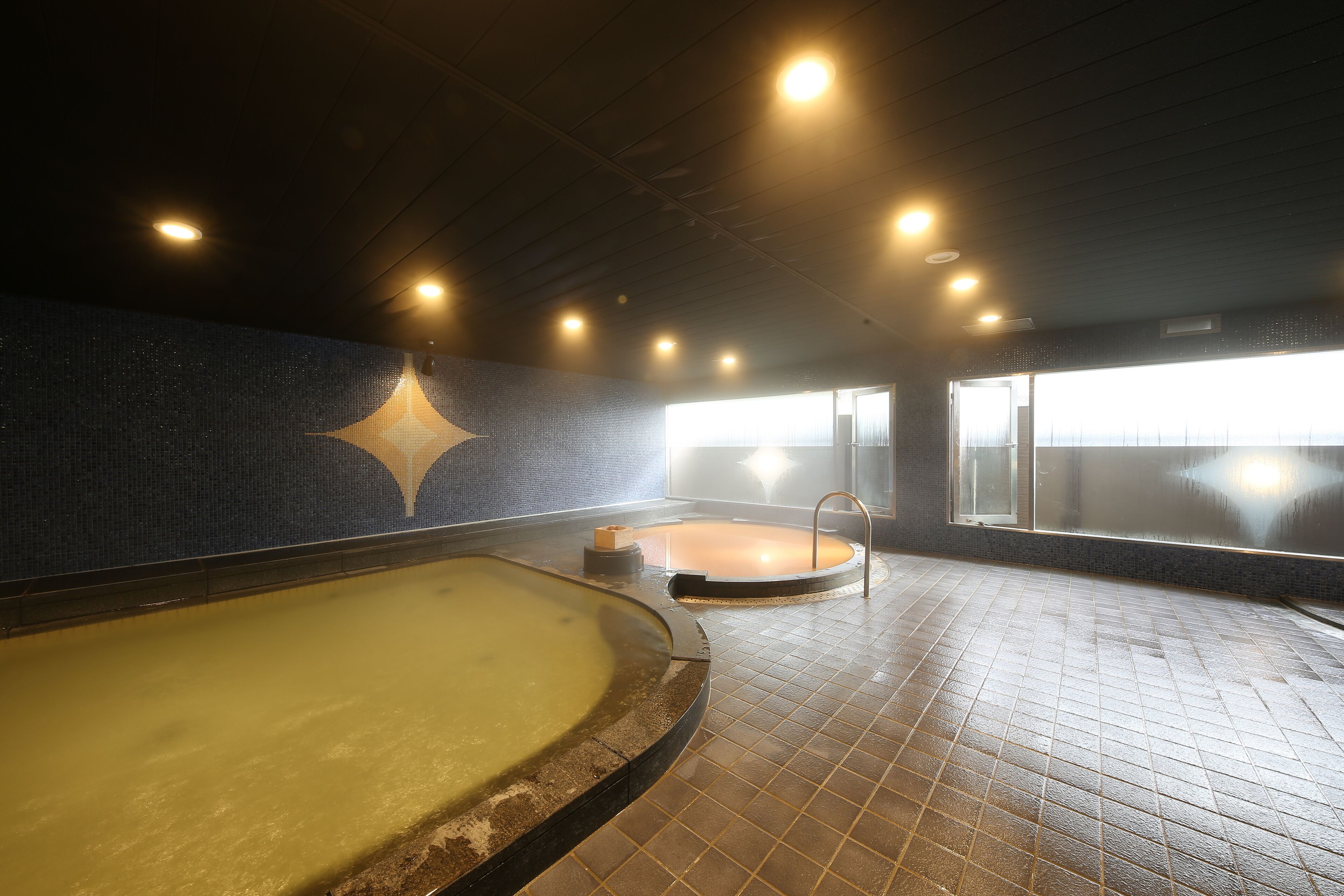 Área de spa com duas banheiras de hidromassagem e uma grande janela que oferece luz natural.