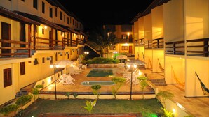 Pátio com piscina, áreas de estar e escadaria que dá acesso aos andares superiores.