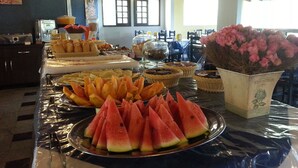 Uma mesa de buffet com diversos alimentos, incluindo fatias de melancia, pão e outros pratos.