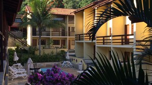 Resort com área de piscina, palmeiras e montanhas ao fundo.