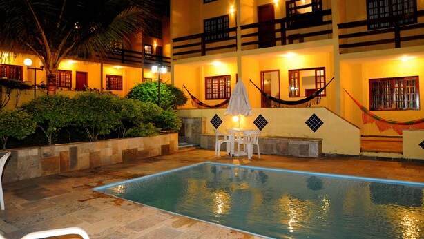 Um pátio de hotel com piscina, área de estar externa e uma palmeira.