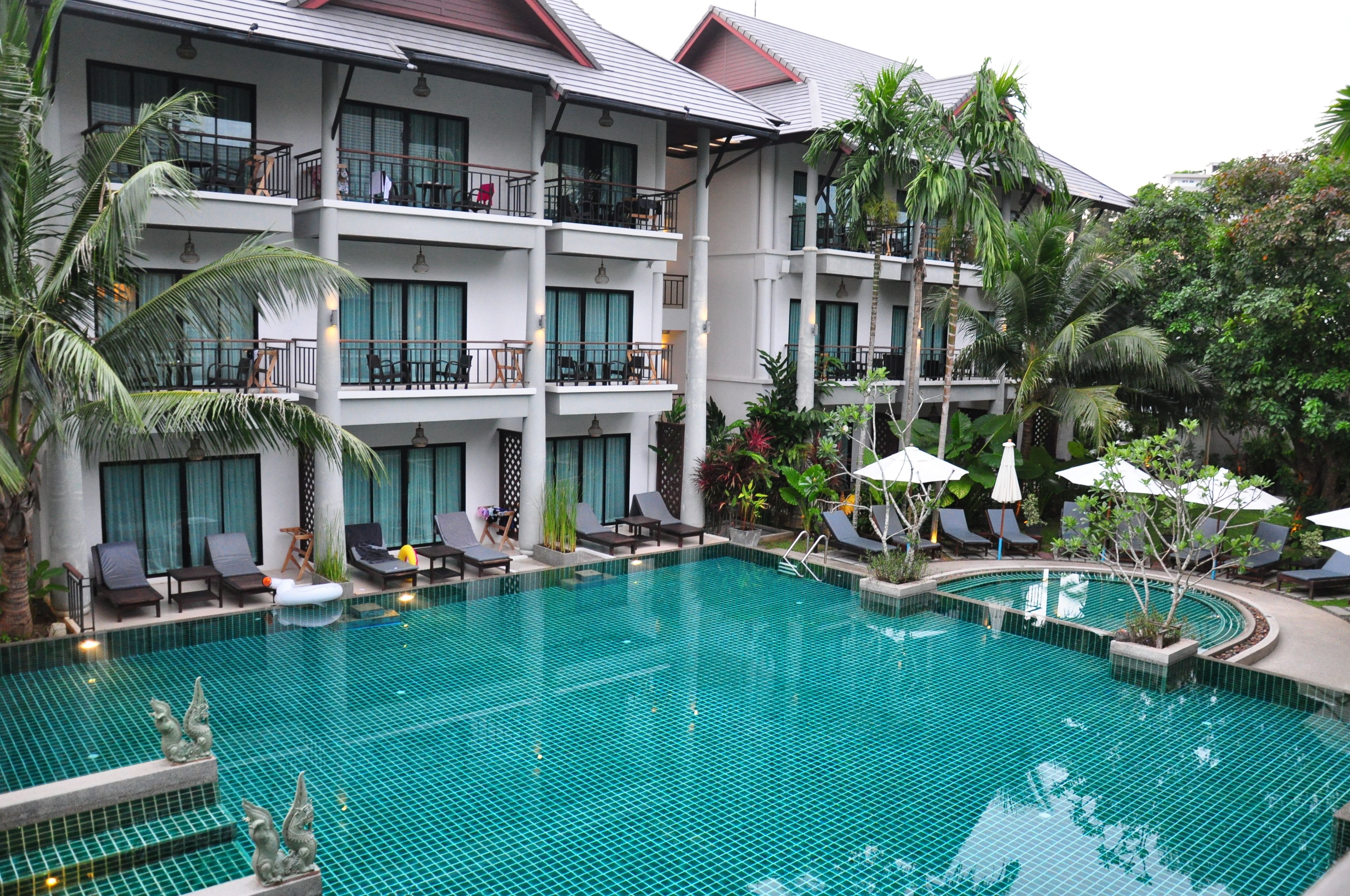 Hotel com uma grande piscina ao ar livre, várias varandas e vegetação exuberante.