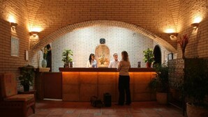Uma área de recepção com um arco de tijolos, um balcão de recepção e plantas em vasos.