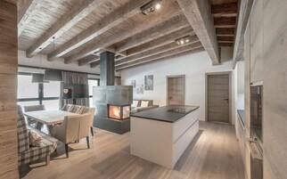 Cozinha moderna com ilha central, área de jantar com mesa e cadeiras, e lareira.