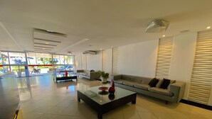 Um hall amplo com design moderno, com uma mesa de centro de vidro, um sofá e um banco.