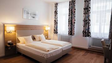 Uma cama de casal com cabeceira de madeira, luminárias de apoio e um quadro na parede.