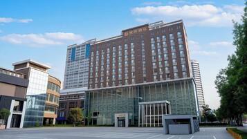 Um hotel moderno com fachada de vidro, entrada central e estacionamento.