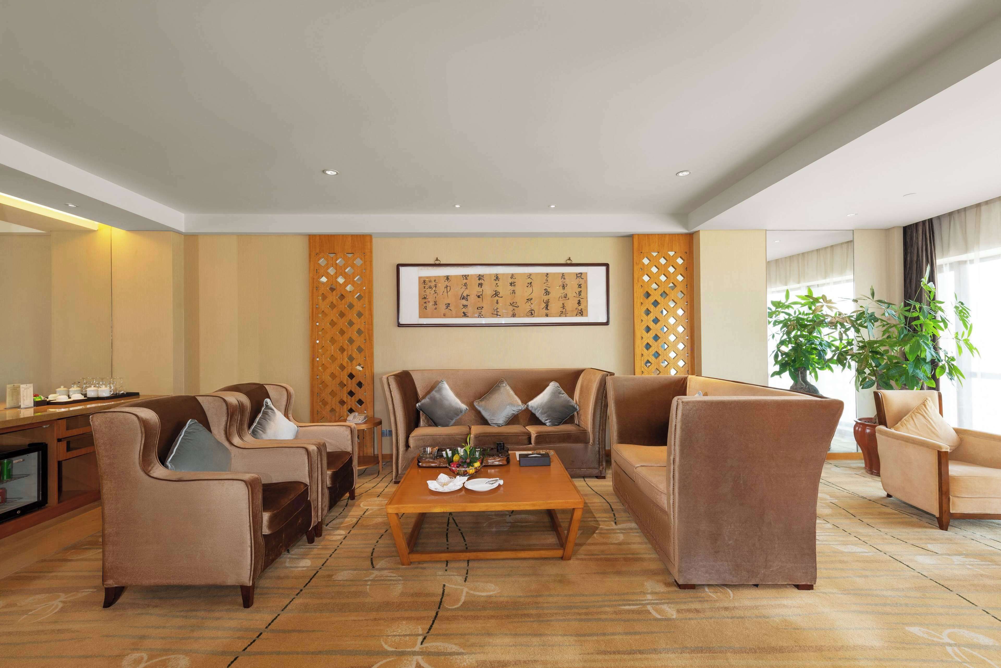 Uma sala de estar ampla com um conjunto de sofás, uma mesa de centro e um objeto decorativo na parede.