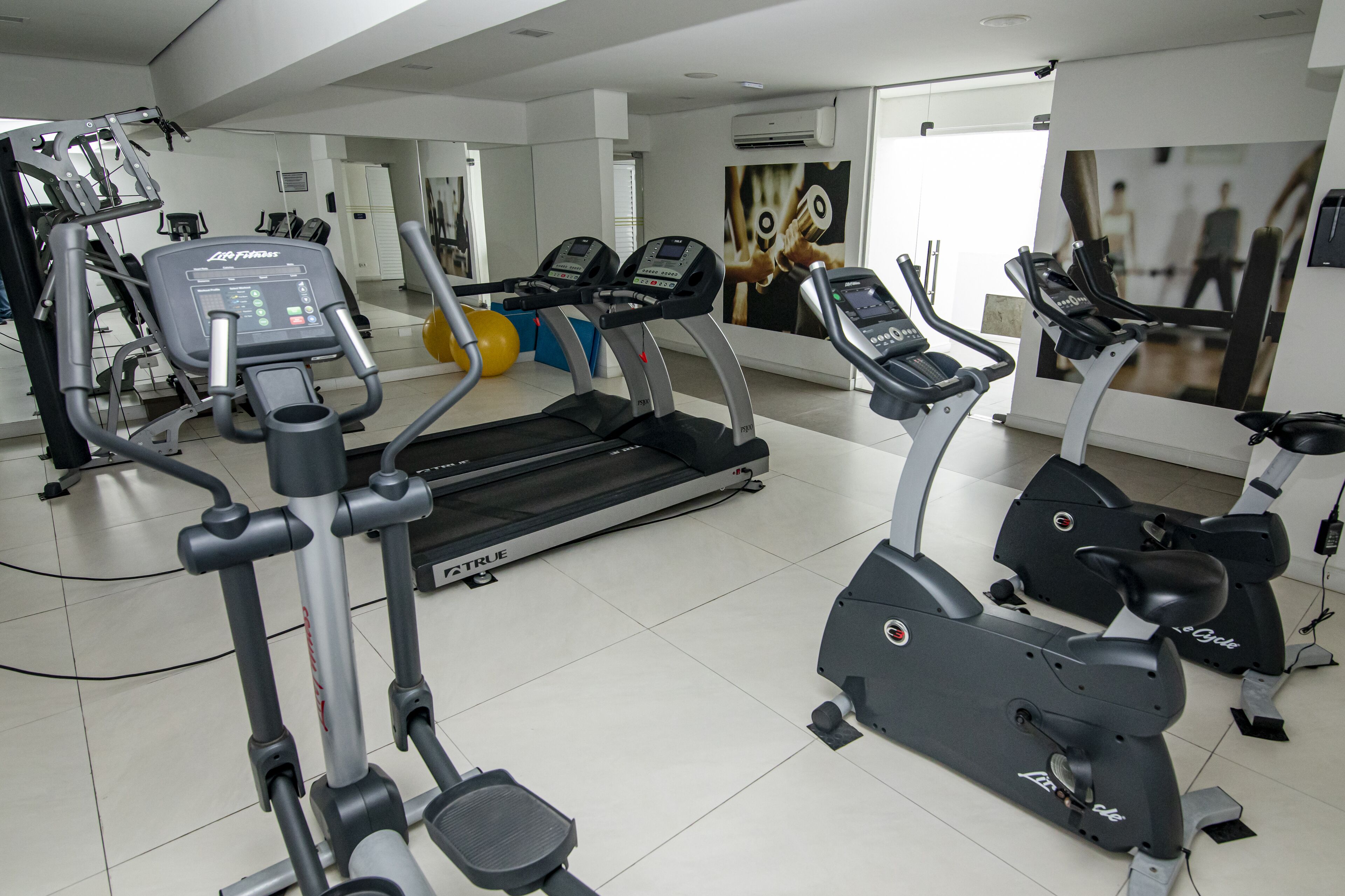 Uma academia com esteiras, elípticos e bolas de exercício.