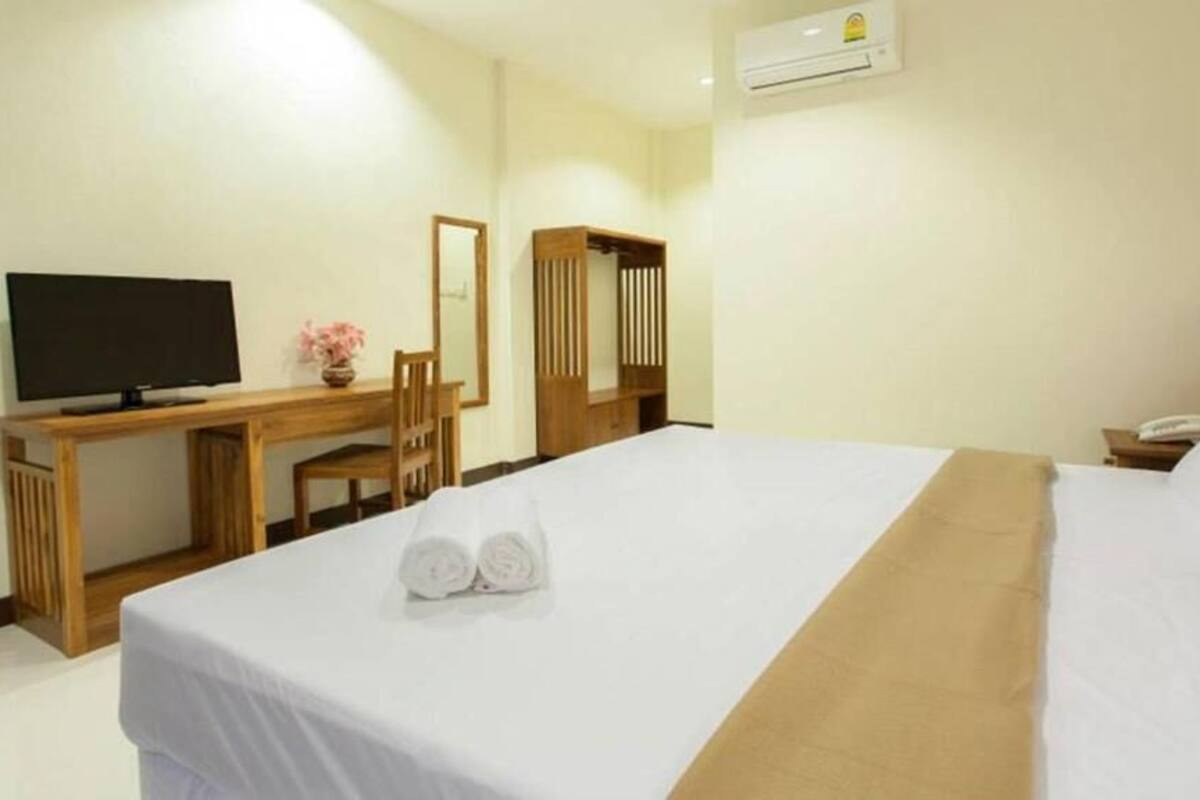 Quarto de hotel com cama, escrivaninha com televisão, espelho e guarda-roupa.